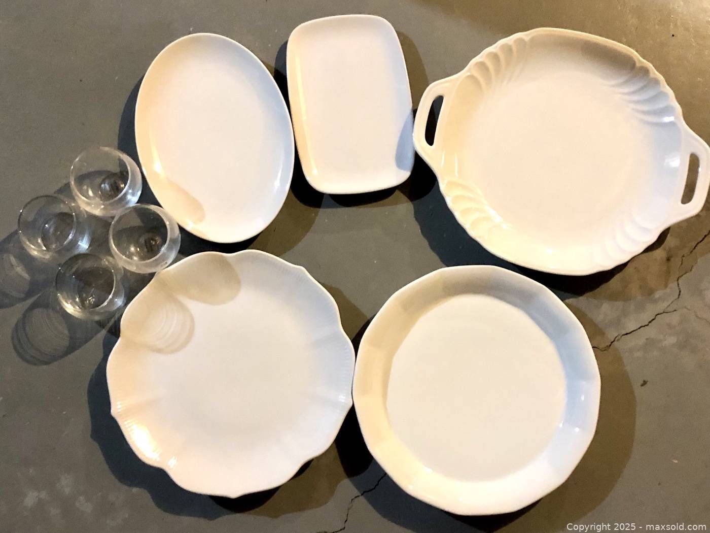 Seven white platters and plates with four glass votive holders | Maxsold